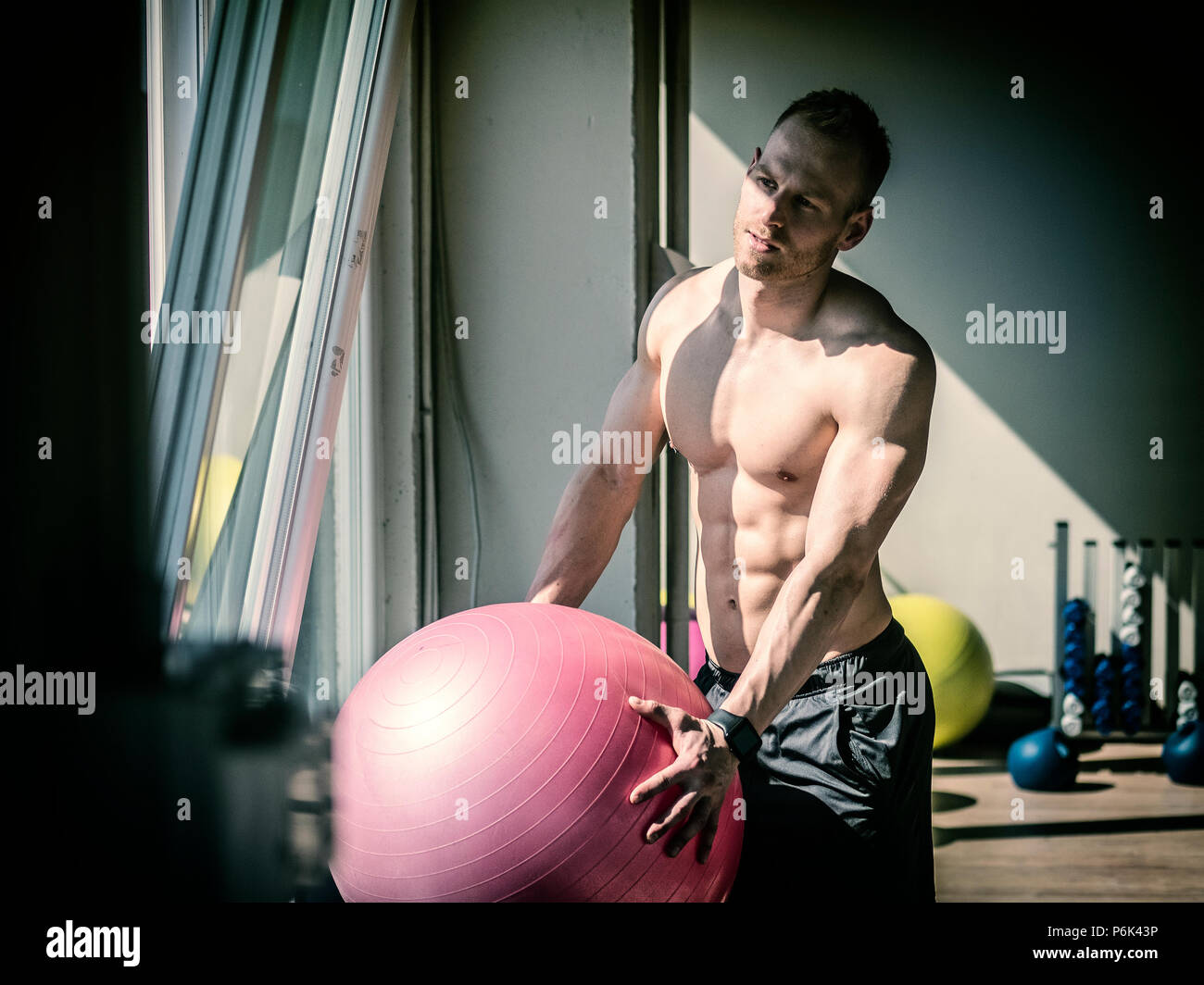 Attractive blond young man shirtless in gym working out, holding ...