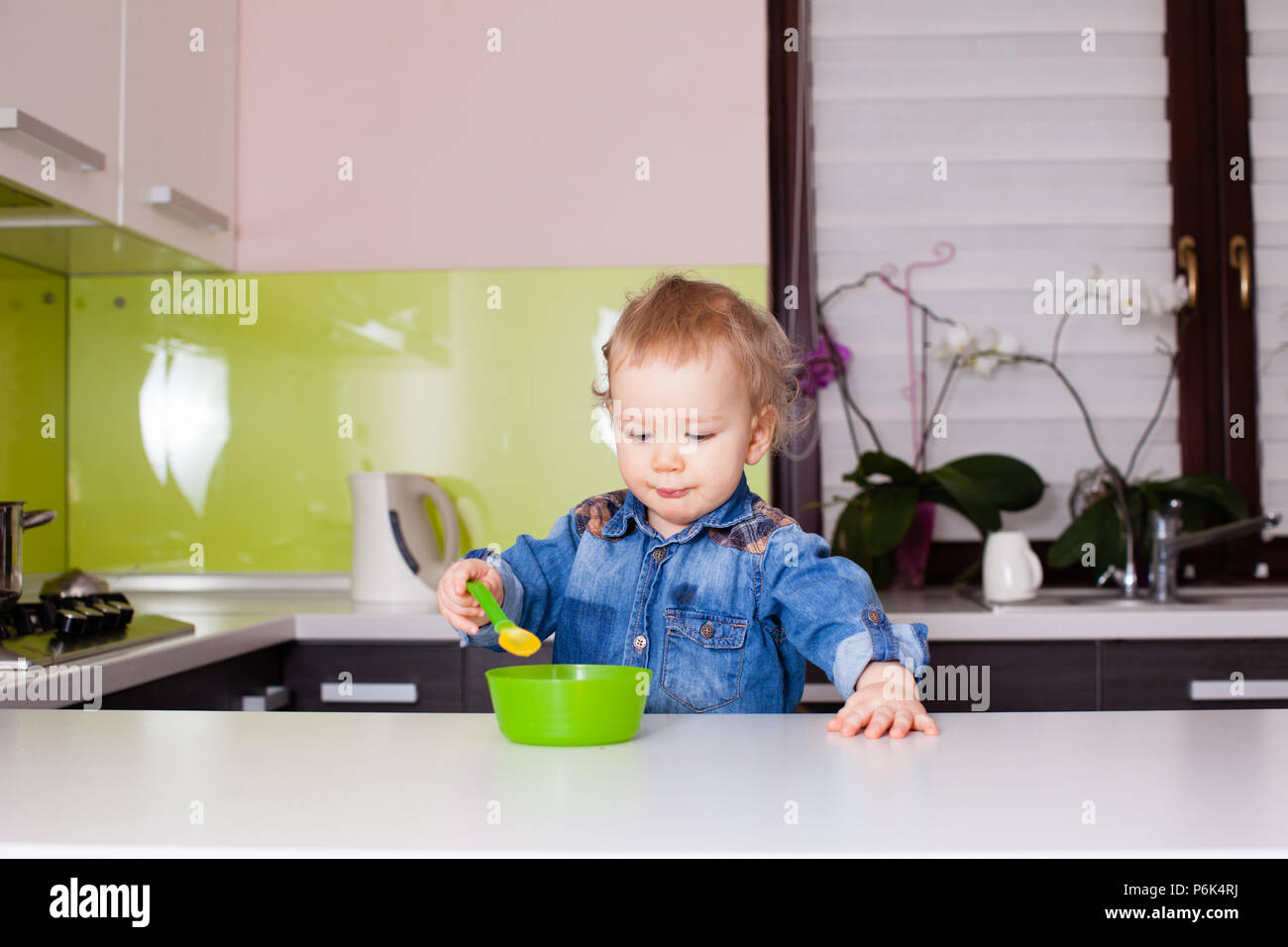 Baby child eats food himself with spoon Stock Photo - Alamy