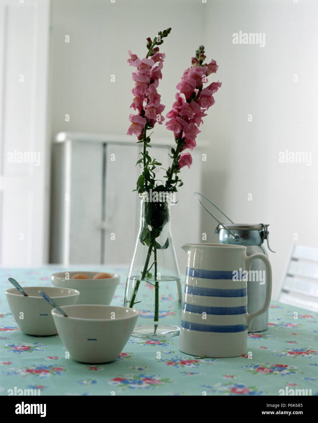 Close-up of vase of pink flowers on dining table with blue striped ...