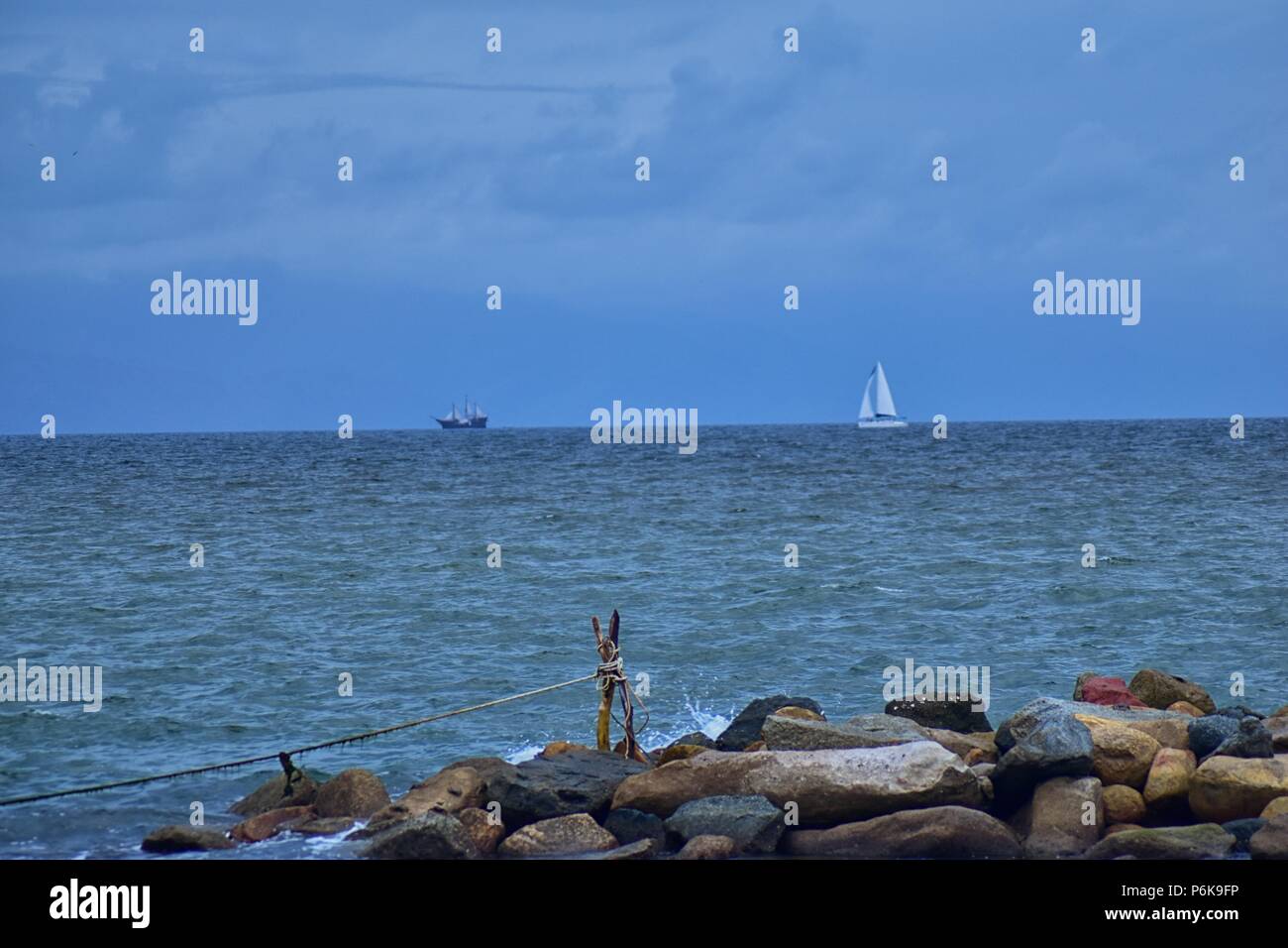 Pirate Ship and Sail Boat off in the distance with rocks in foreground ...