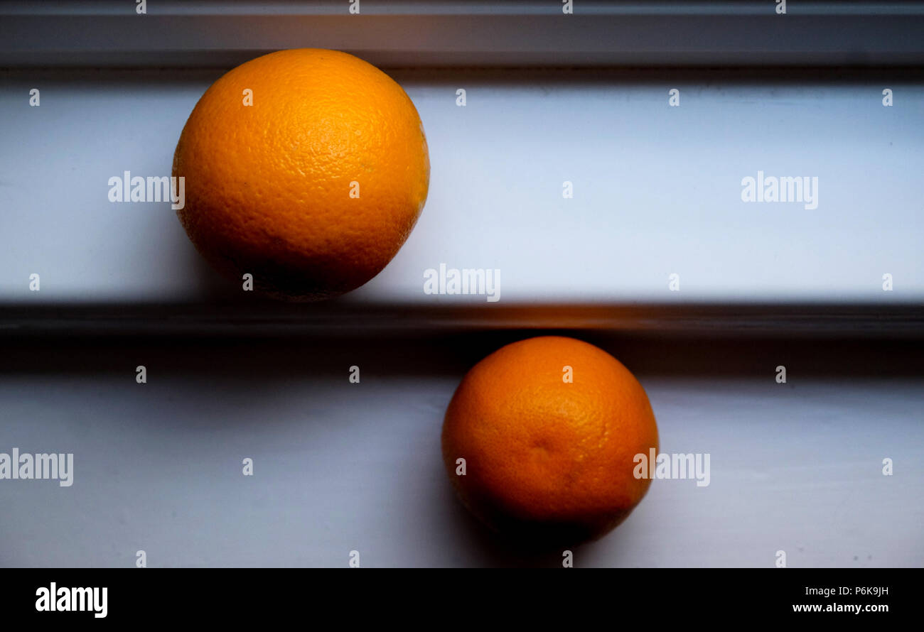 two oranges on a white layered background the orange on the left is ...