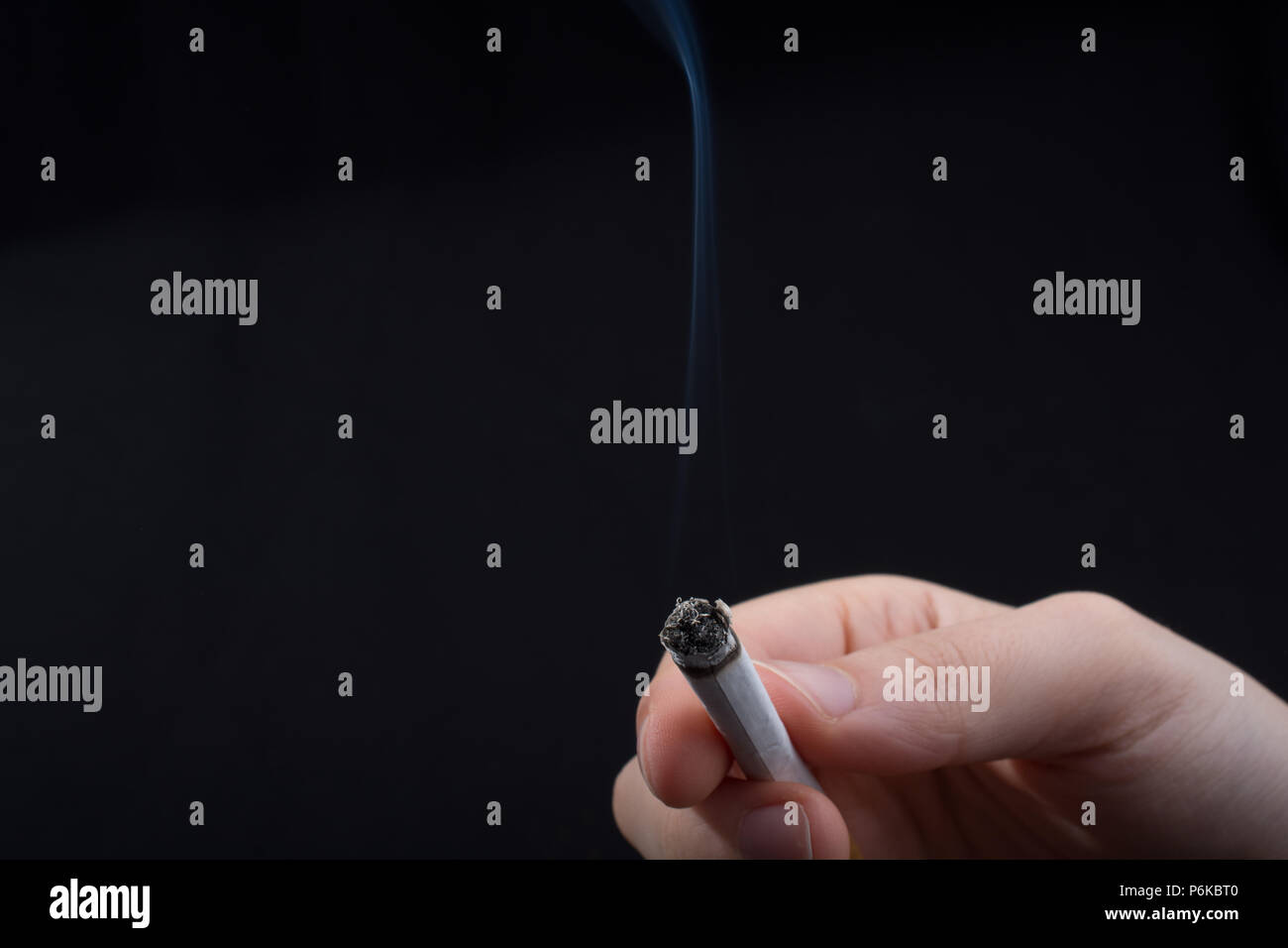 Hand is holding smoking cigarette with smoke around Stock Photo - Alamy