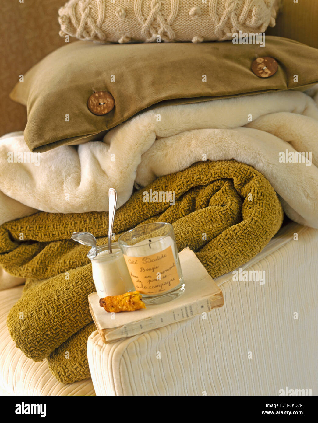 Close-up of light brown velvet cushion with folded cream faux fur throw ...