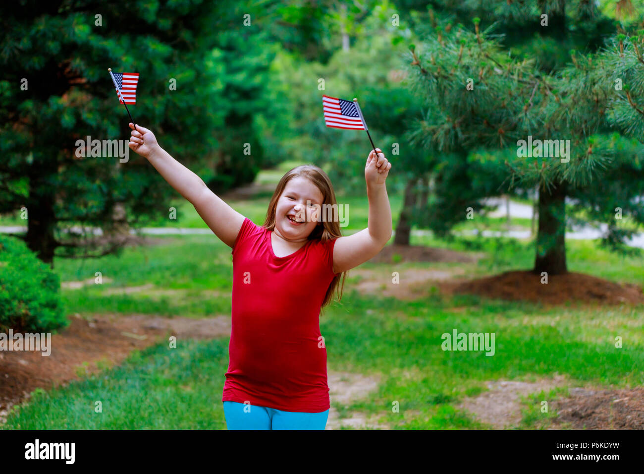 Happy elementary age little girl smiles while holding American flag in ...