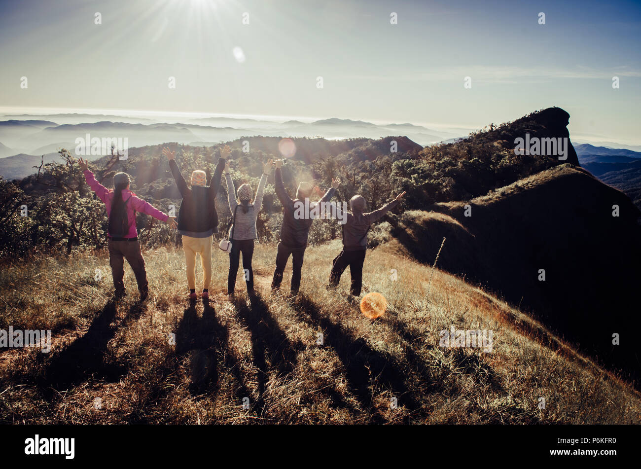 Group of Traveler on mountain summit enjoying aerial view hands raised ...