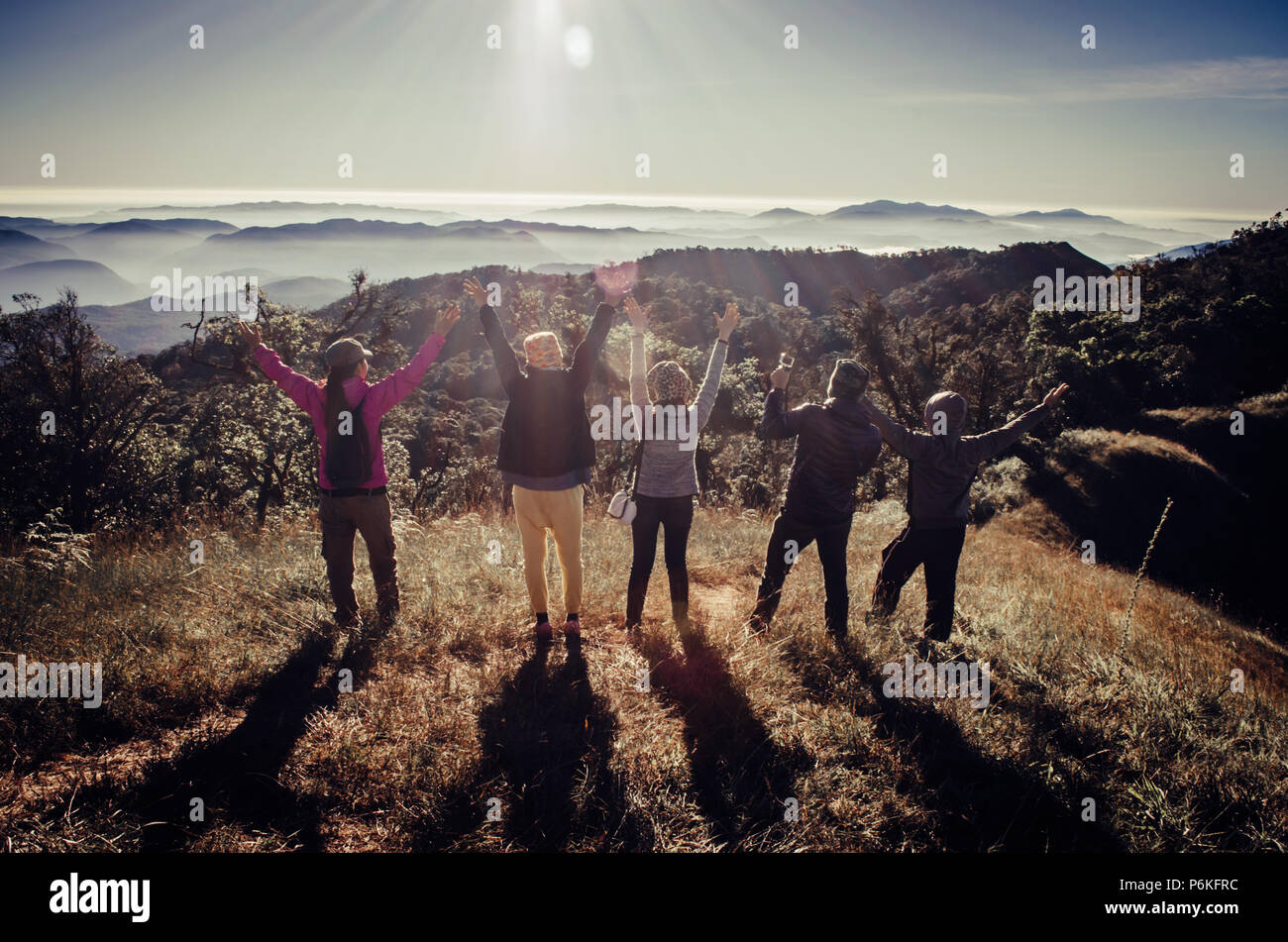 Group of Traveler on mountain summit enjoying aerial view hands raised ...