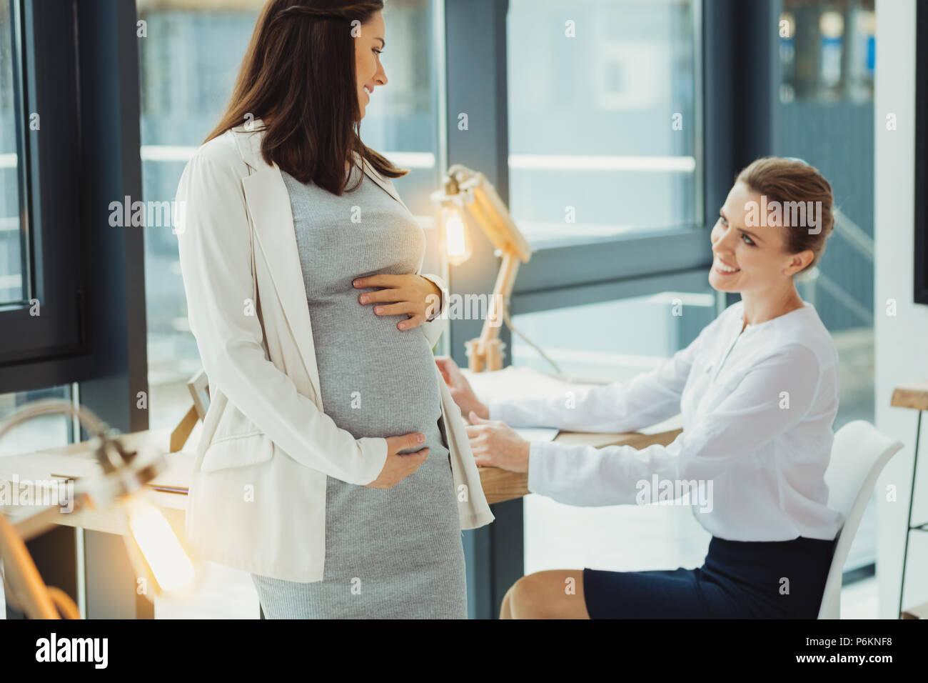 Pretty pregnant woman turning to her colleague and smiling Stock Photo ...