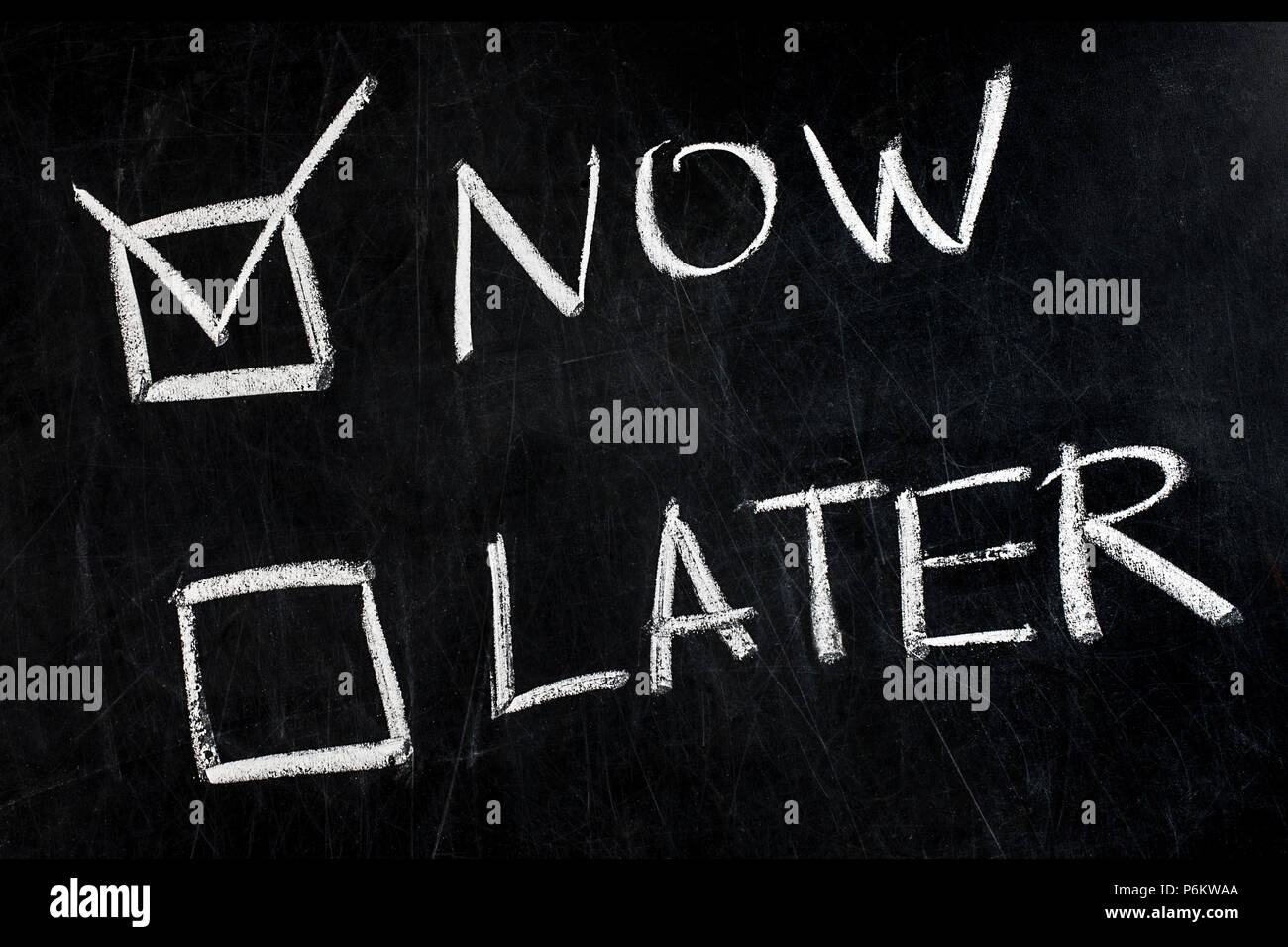 Now and Later check boxes handwritten with white chalk on blackboard ...