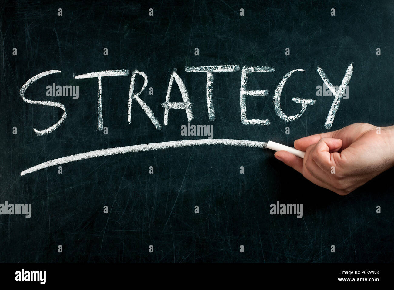 Hand with white chalk underlining handwritten strategy text on ...