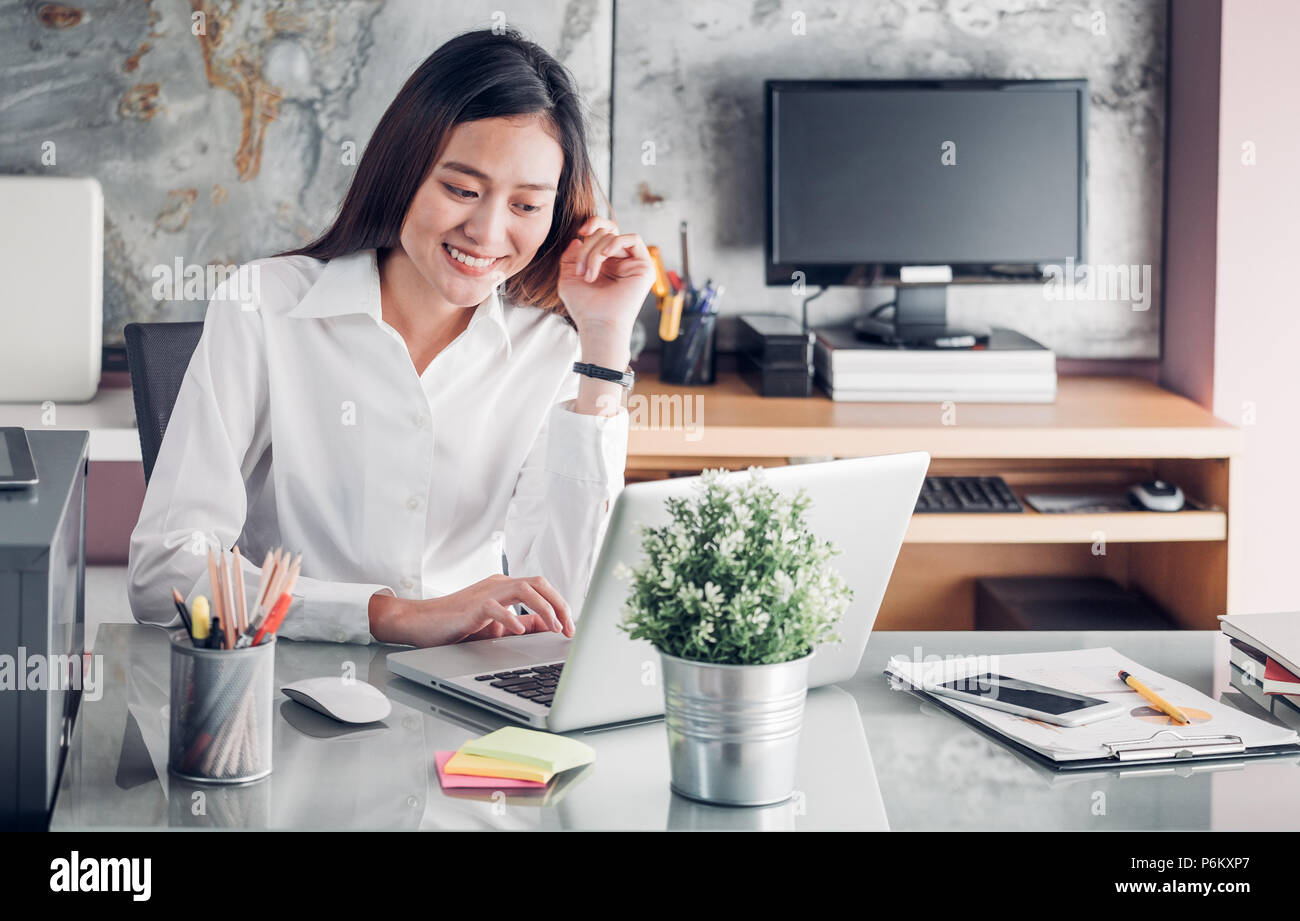 Asia businesswoman looking at laptop computer and smiling face and rest ...
