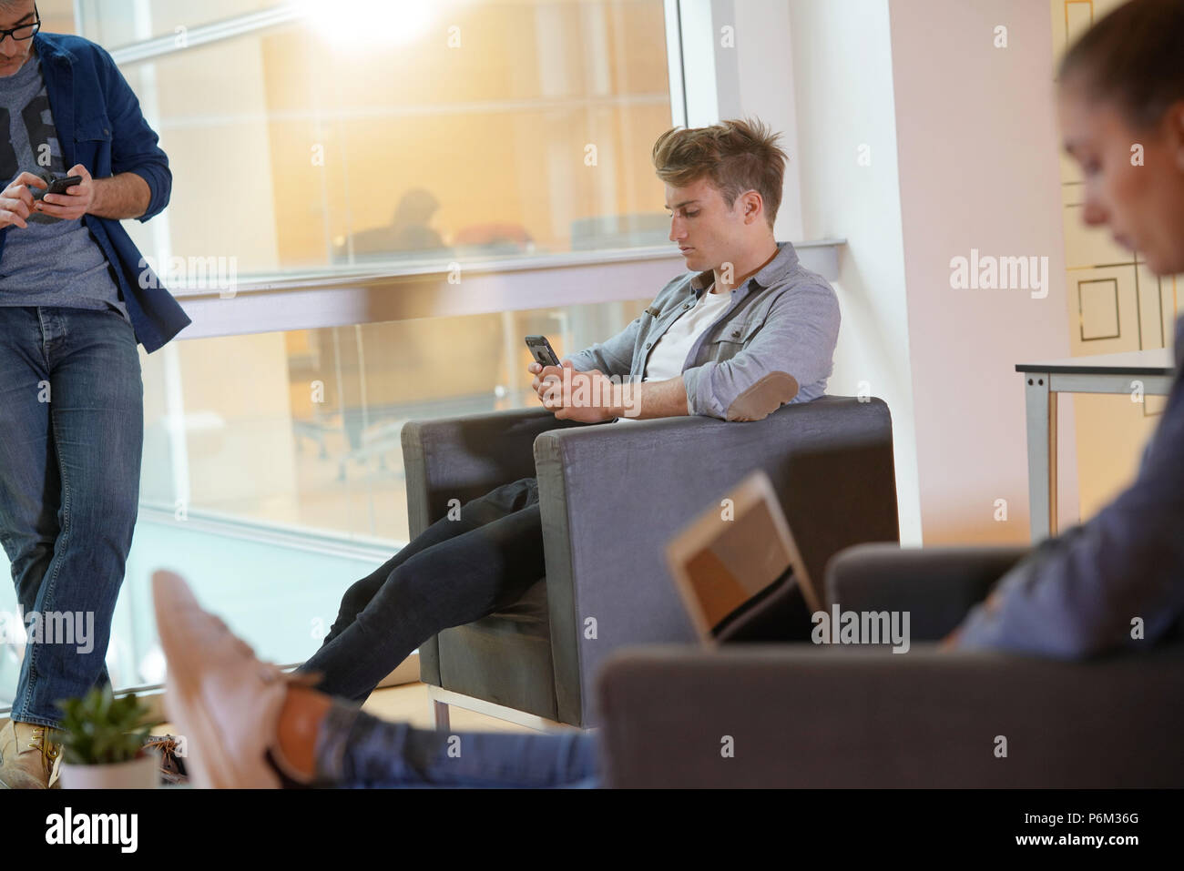 Young people relaxing in lounge room, connected Stock Photo - Alamy