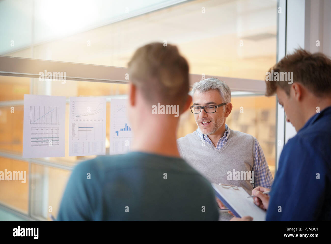 Teacher in classroom teaching economics to young people Stock Photo - Alamy
