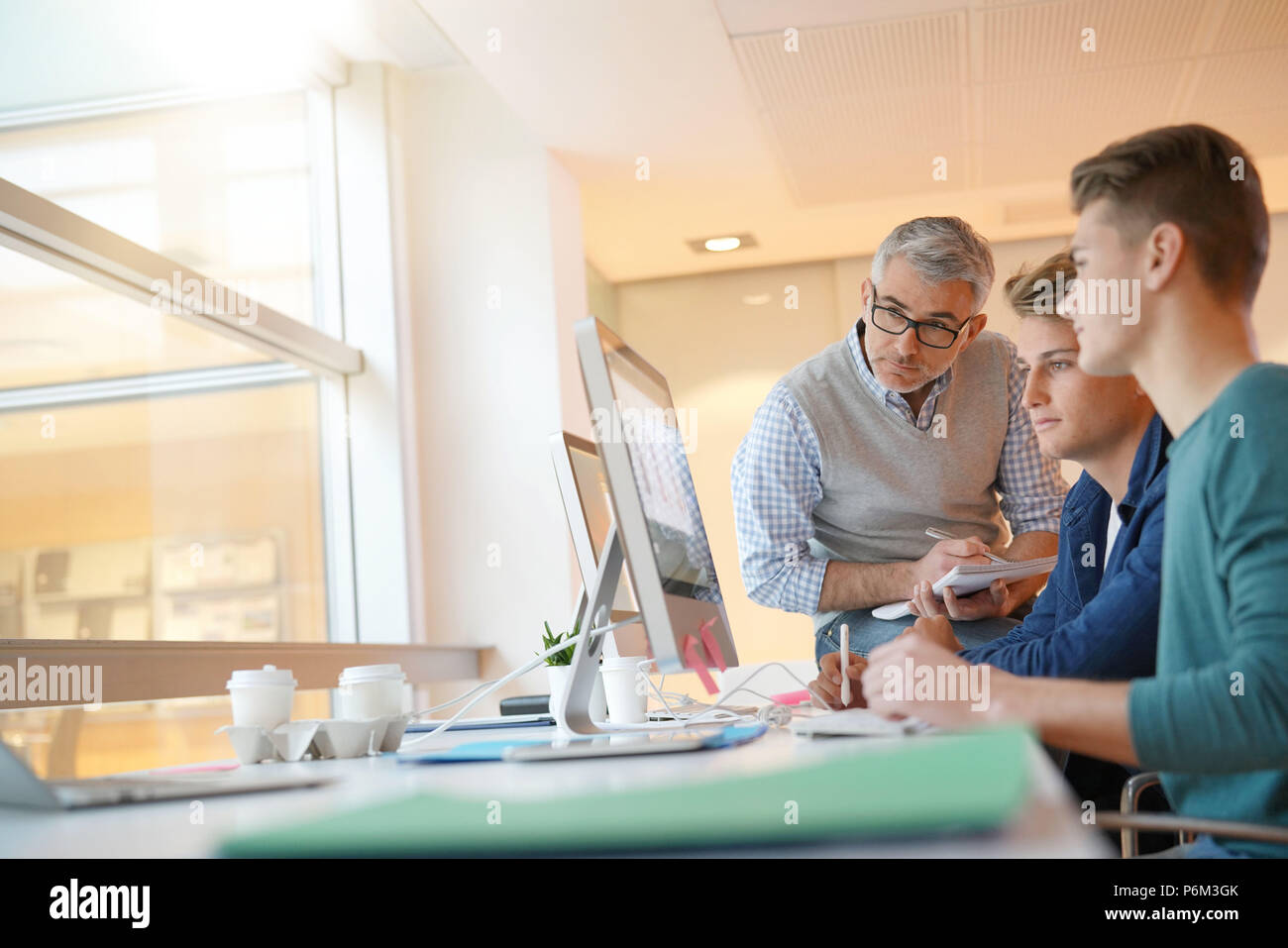 Teacher with students in computing class Stock Photo - Alamy