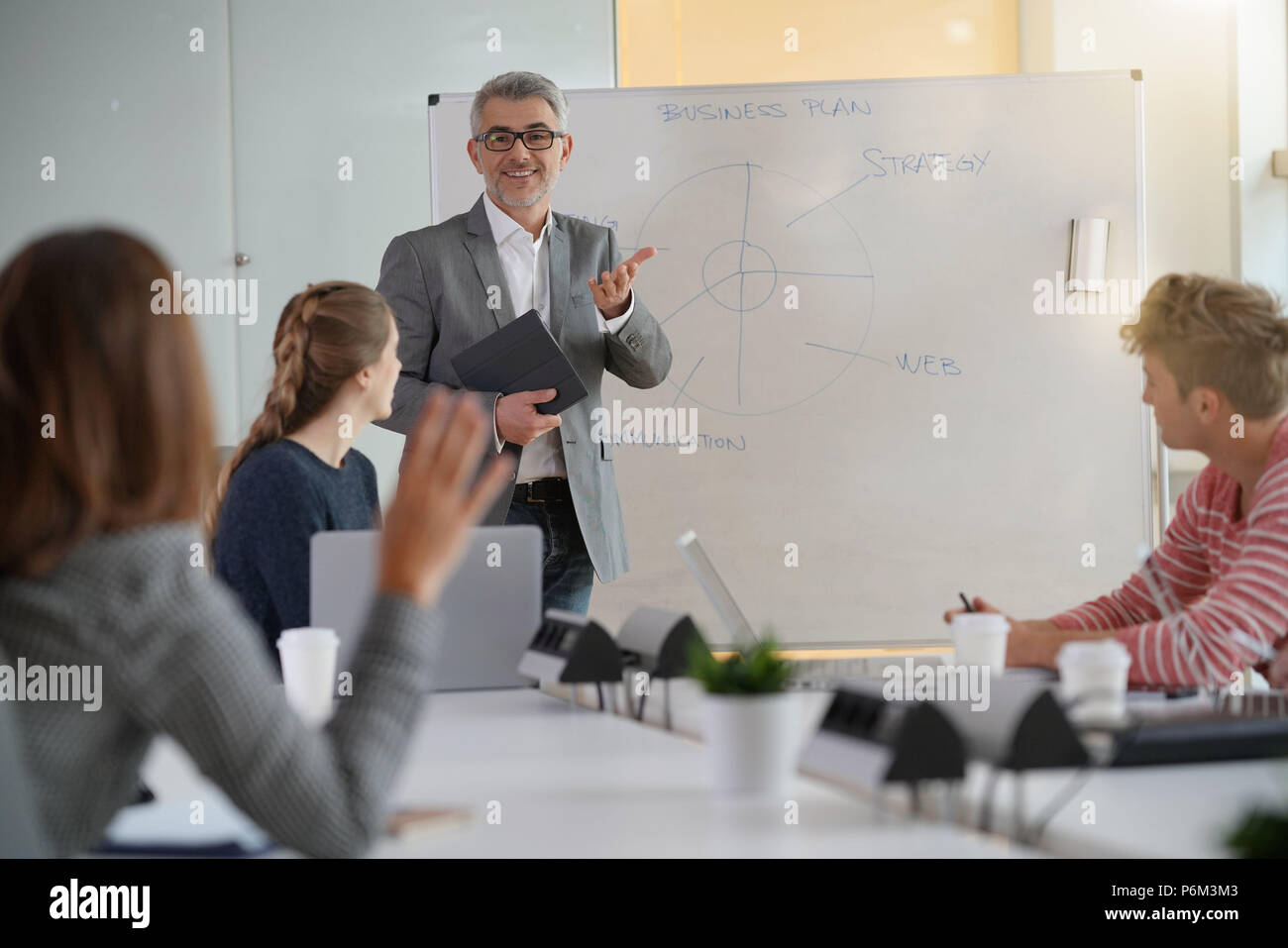 Teacher giving economics class, using whiteboard Stock Photo - Alamy