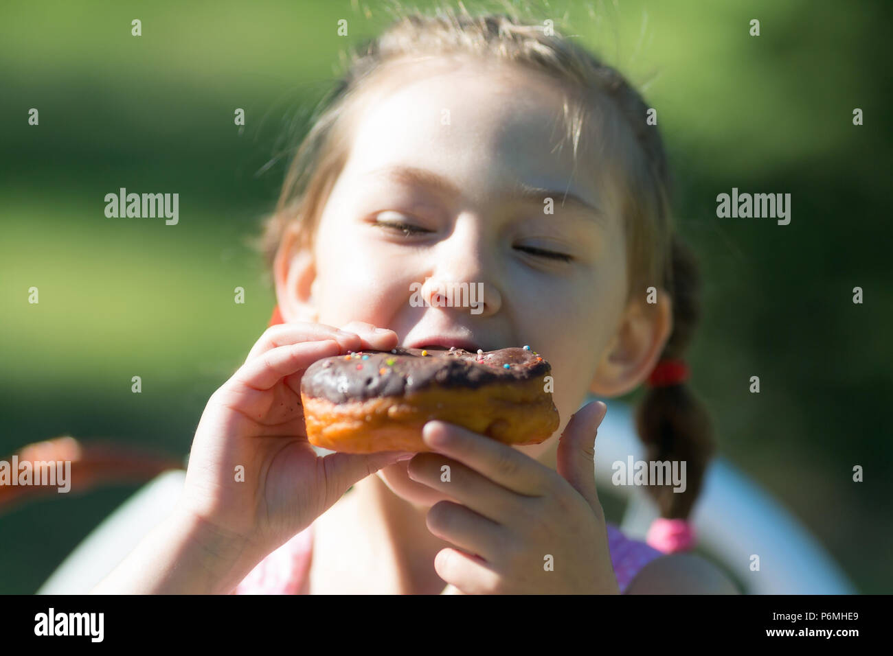 A beautiful girl bites a big sweet bun Stock Photo - Alamy