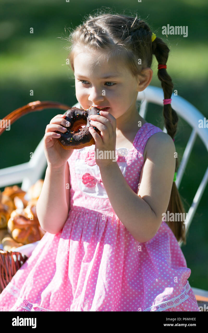 A beautiful girl bites a big sweet bun Stock Photo - Alamy