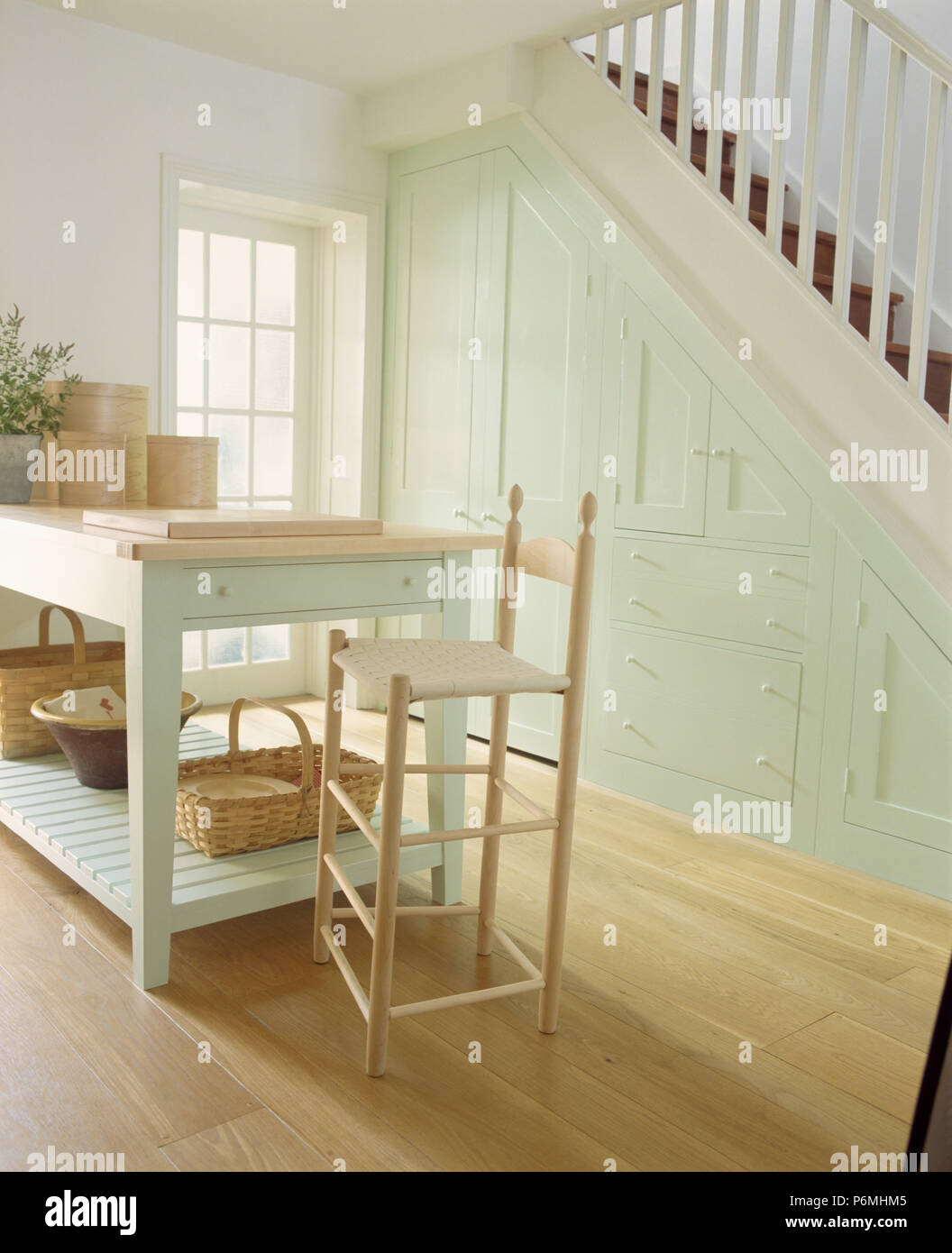 Pale wood Shaker-style stool at table in hall kitchen with under-stair ...