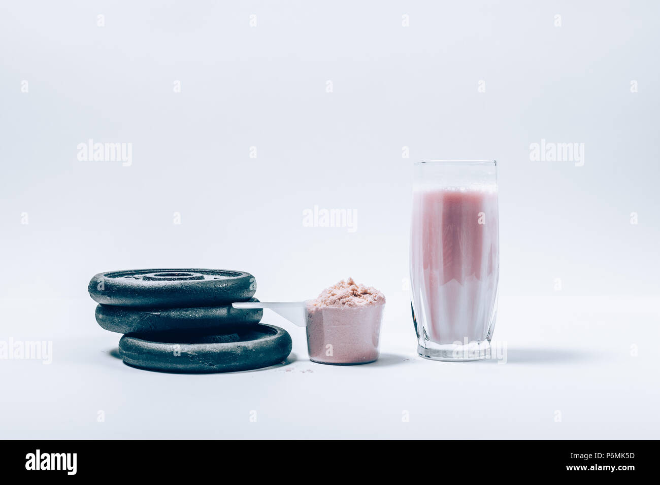Whey protein shake in glass next to scoop of dry powder and stack of ...