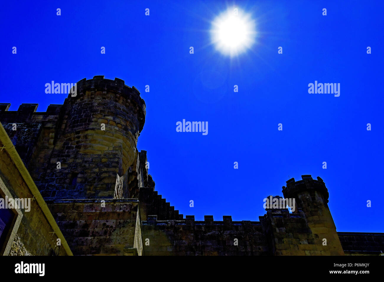 Belsay Castle and turrets silhouetted against the sun and deep blue sky ...