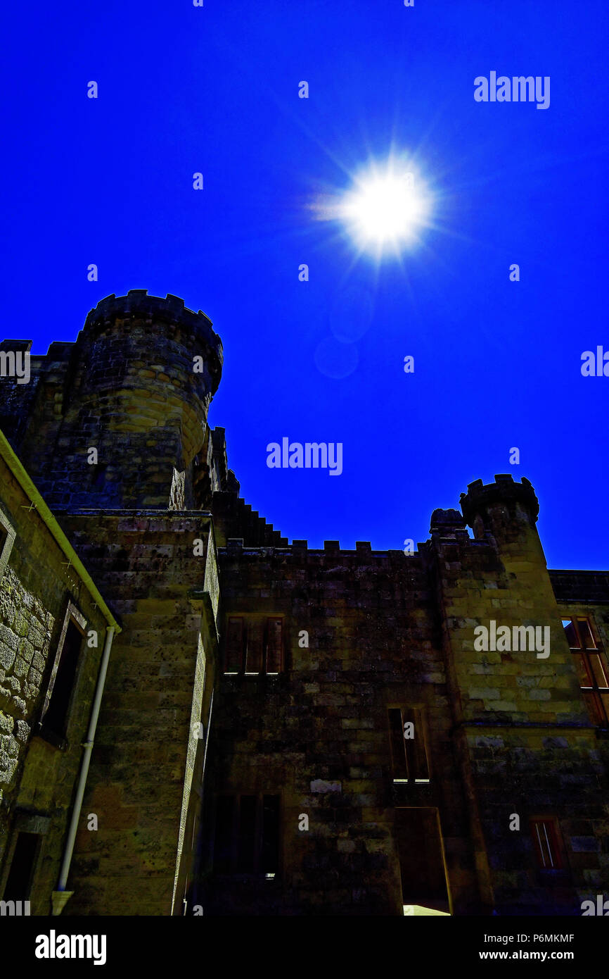 Belsay Castle and turrets silhouetted against the sun and deep blue sky ...
