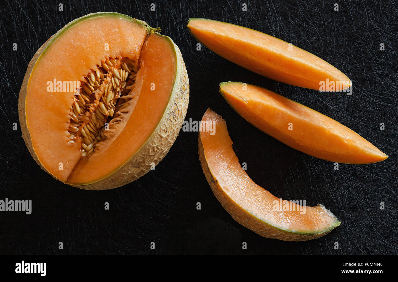 Sliced ripe melon on black background, dark style food seen from above ...