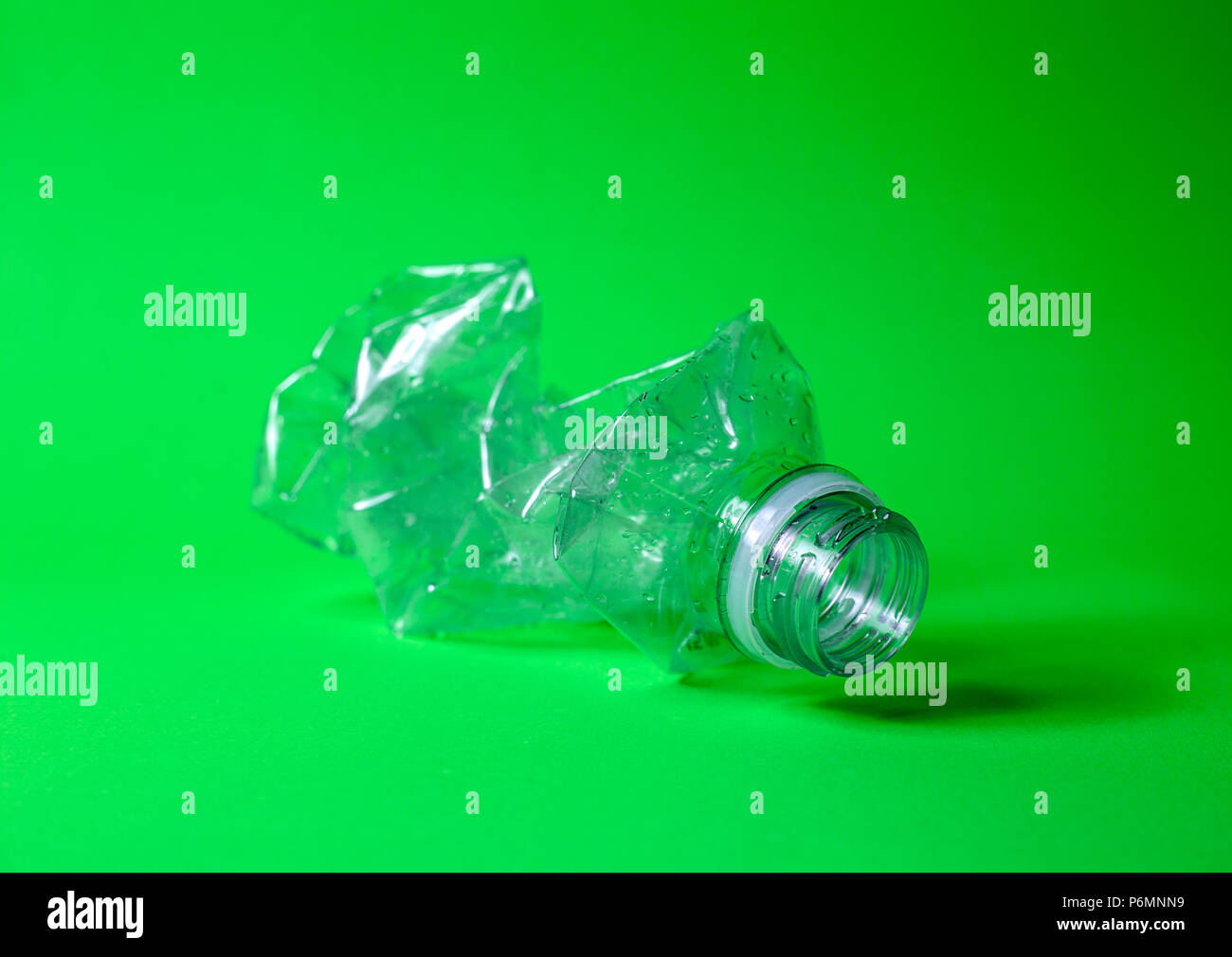 plastic bottle squashed on green background recycle Stock Photo - Alamy