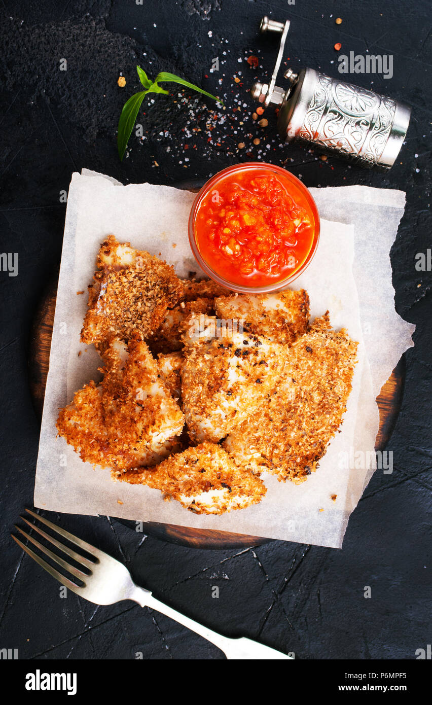 Pan fried fish with tomato sauce on a table Stock Photo - Alamy