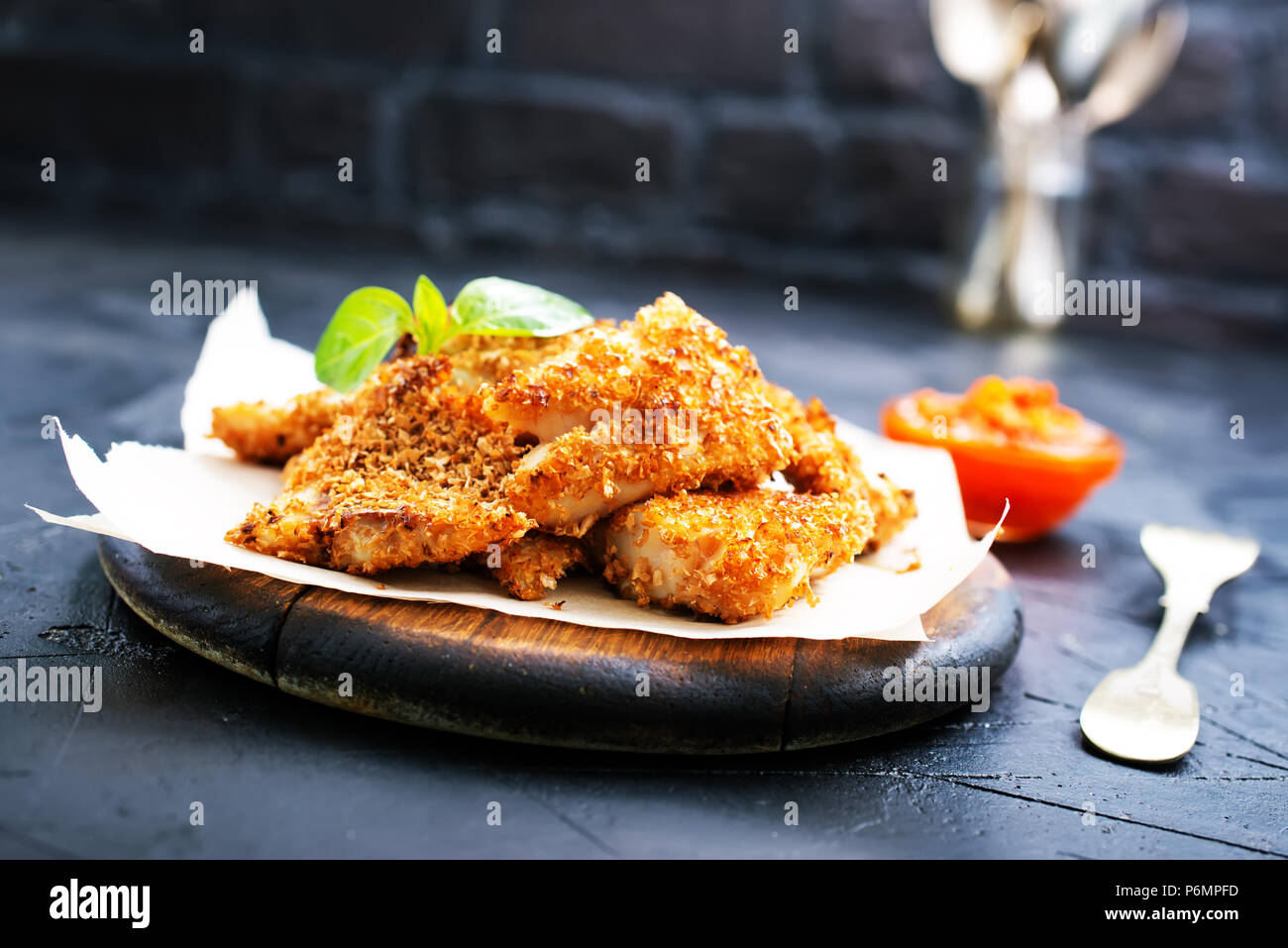 Pan fried fish with tomato sauce on a table Stock Photo - Alamy