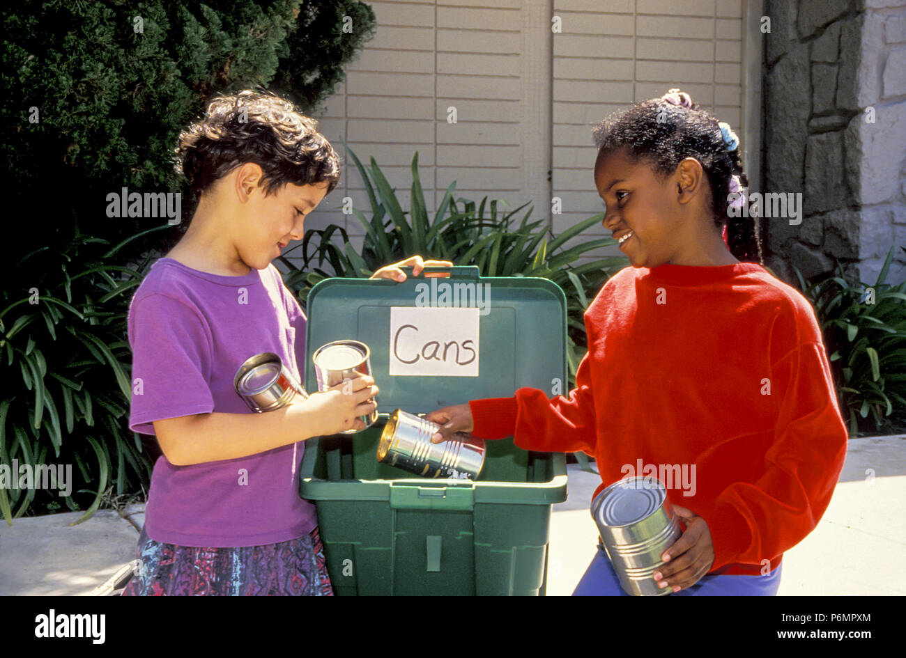 two children putting cans in recycle bin. MR © Myrleen Pearson Stock ...