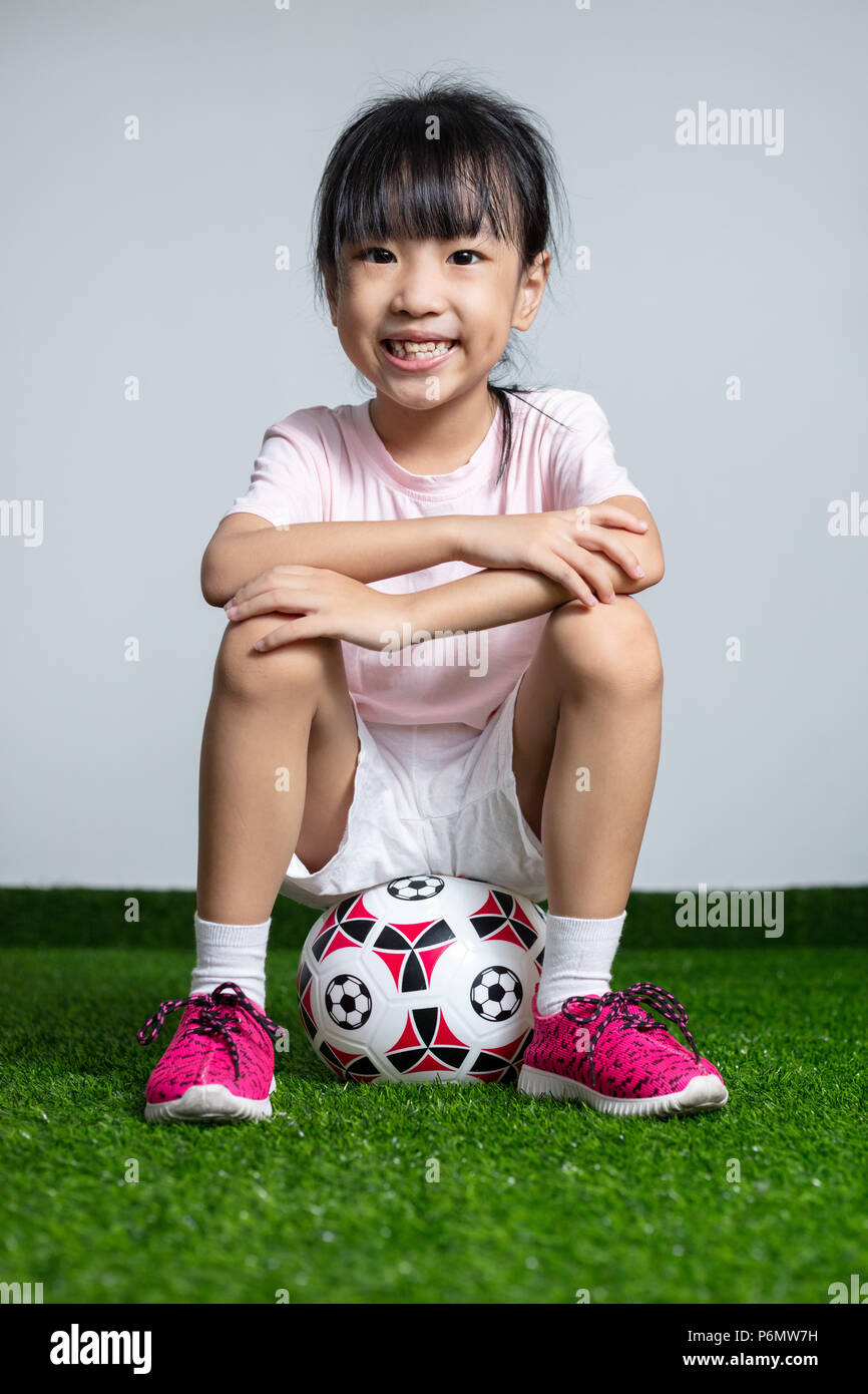 Asian Little Chinese Girl sitting on football in football field Stock ...