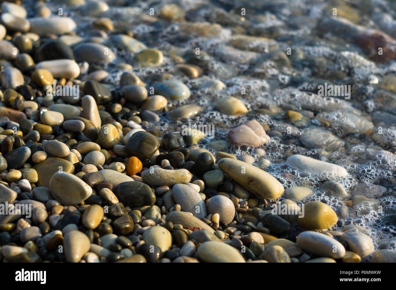 pebble stones on the sea beach on a warm summer day, the rolling waves ...