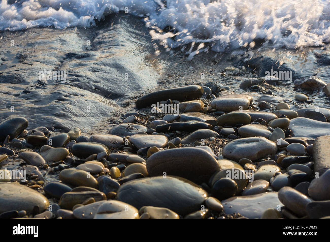 pebble stones on the sea beach on a warm summer day, the rolling waves ...