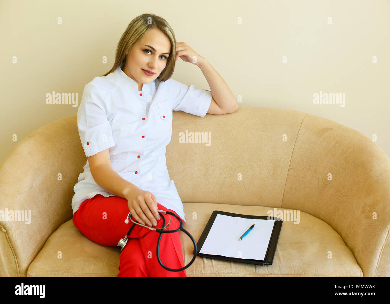 Female doctor in uniform with a stethoscope sitting on the couch and ...