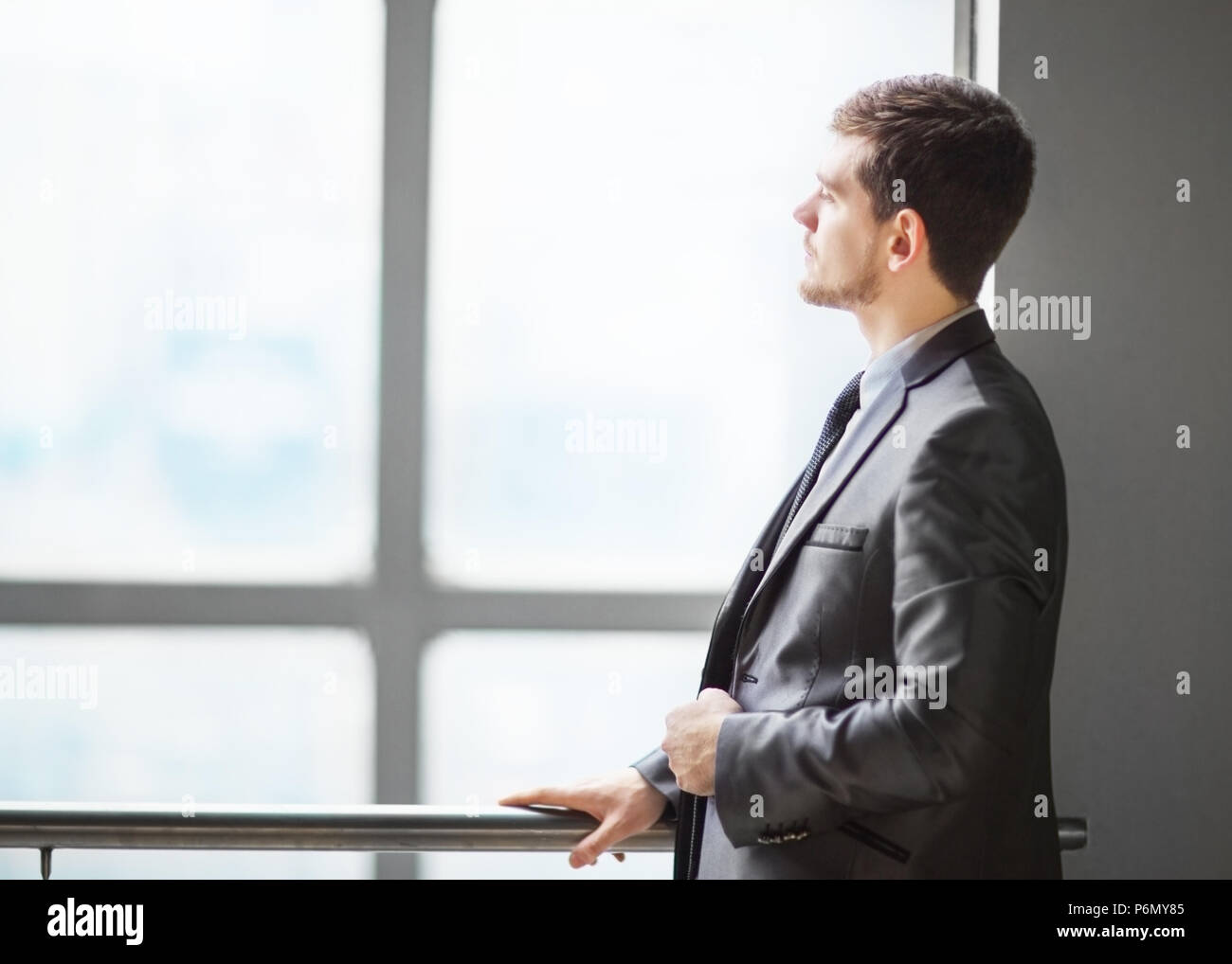 Portrait of a smiling handsome businessman looking out the window with ...