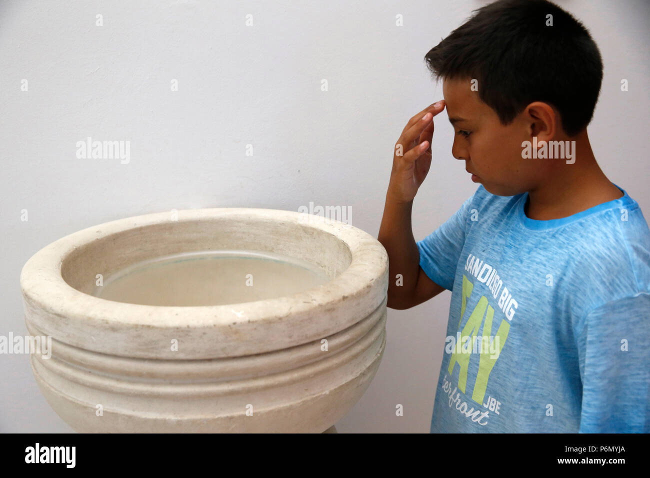 11-year-old boy making a sign of the cross in a Pugliese church, Italy ...