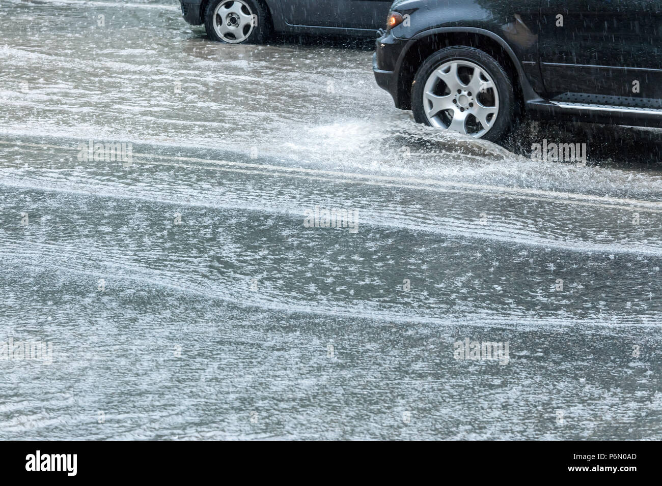 big water puddle on city road. car traffic during heavy rain Stock ...