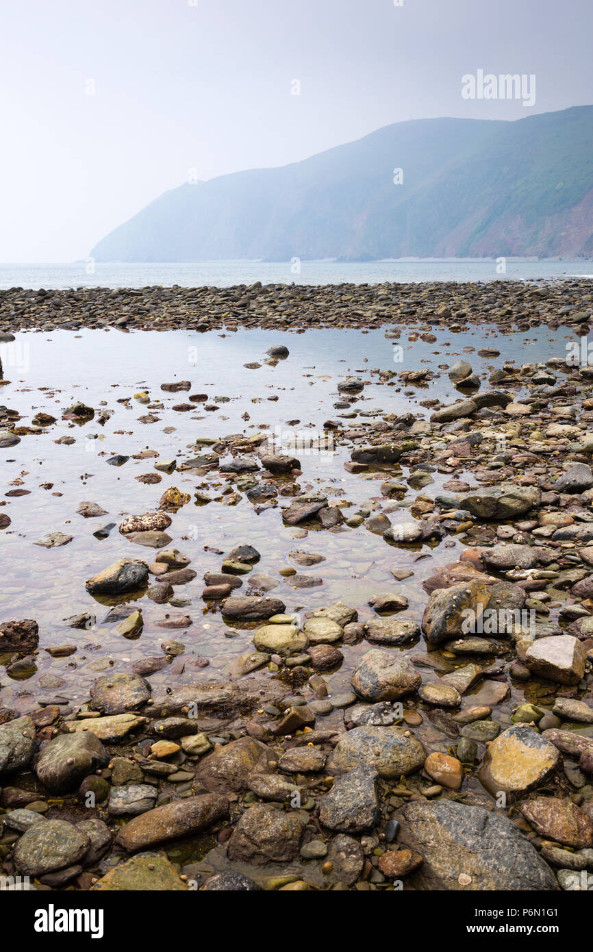 The rocky beach at Lynmouth, North Devon, with reflection and view ...