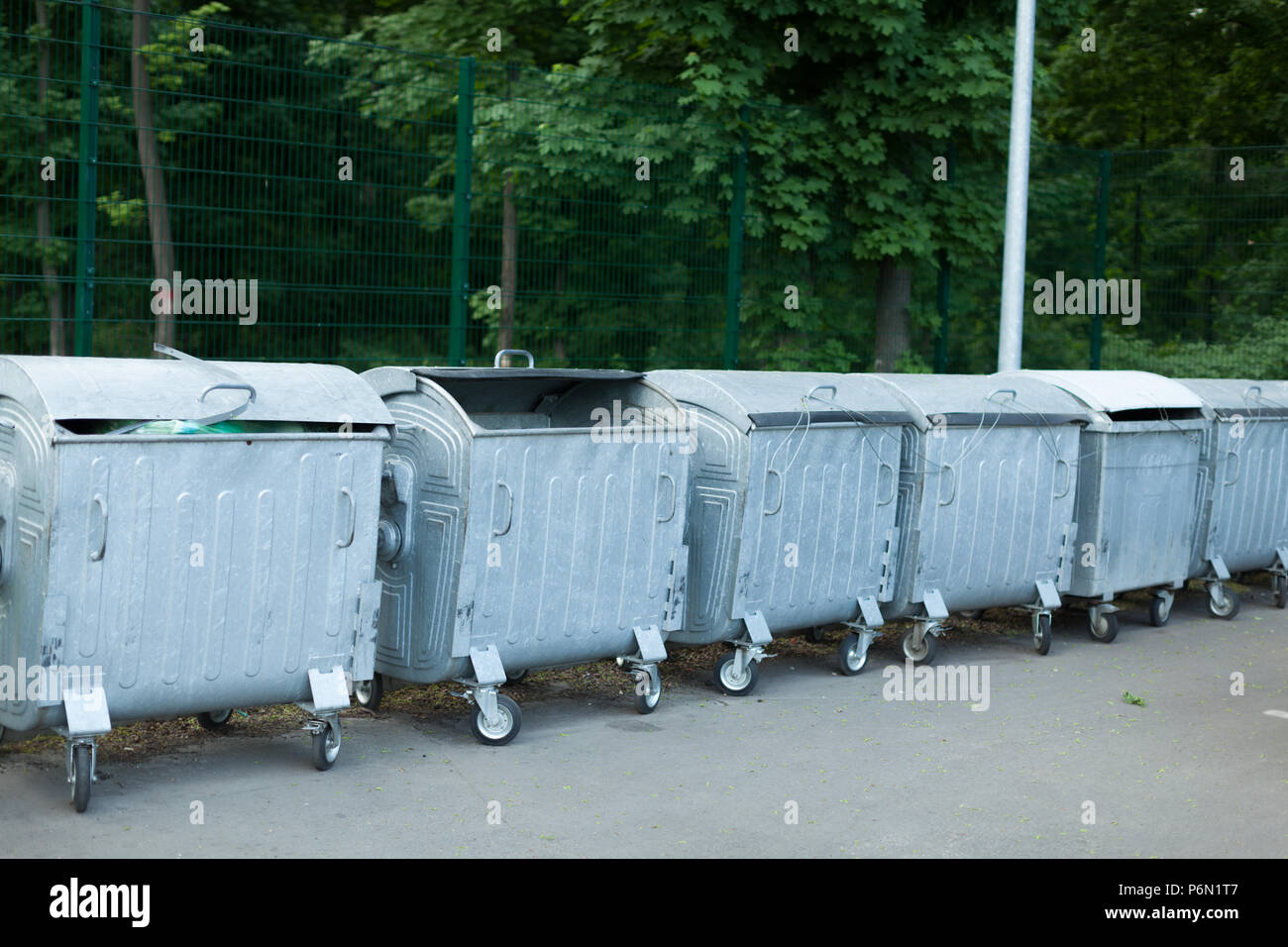 Large metal filled garbage containers on the street standing in a row ...