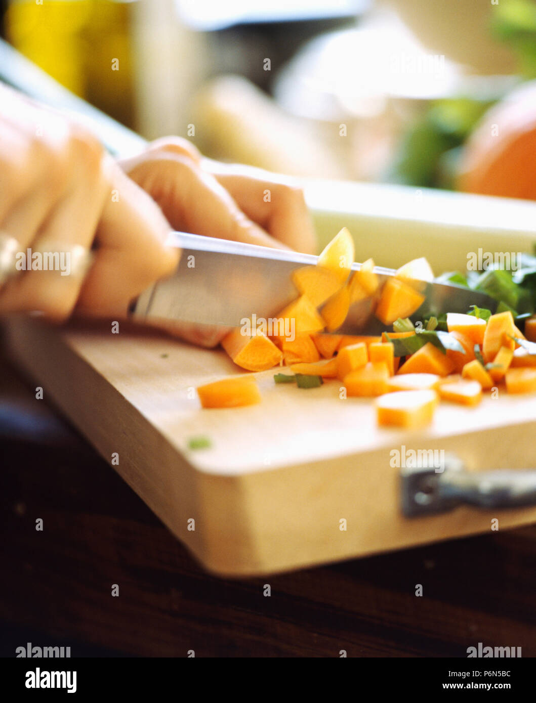 Close-up of hand using sharp knife to chop carrots and cucumber FOR ...