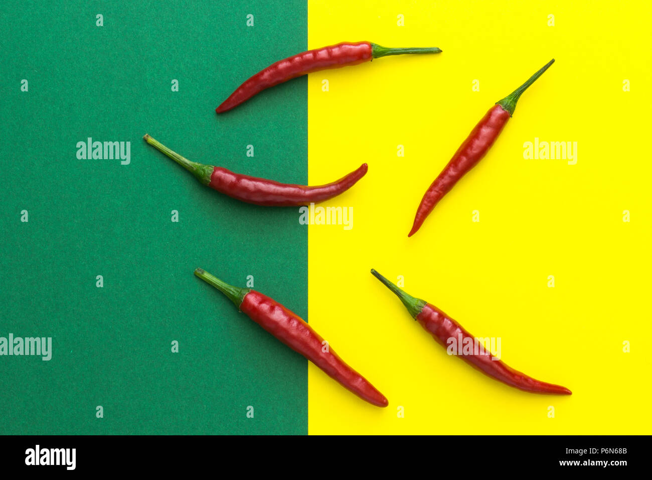 five red chili peppers on a yellow-green background Stock Photo - Alamy