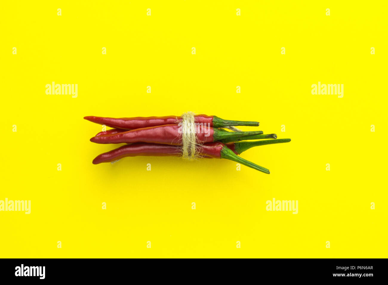 top view, red chili pepper, tied with braid on a yellow background ...