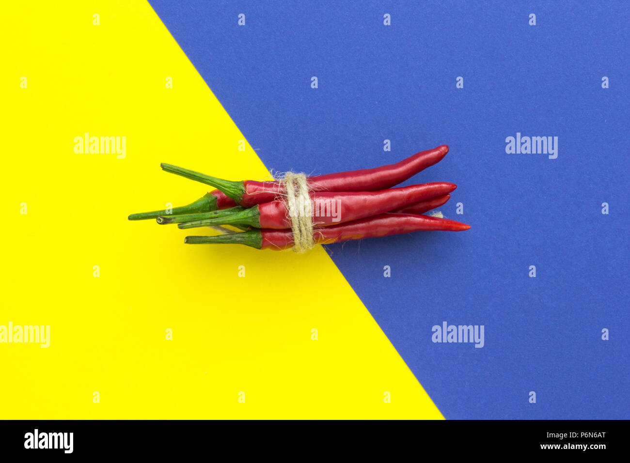 top view, red chili pepper, tied with braid on a yellow-blue background ...