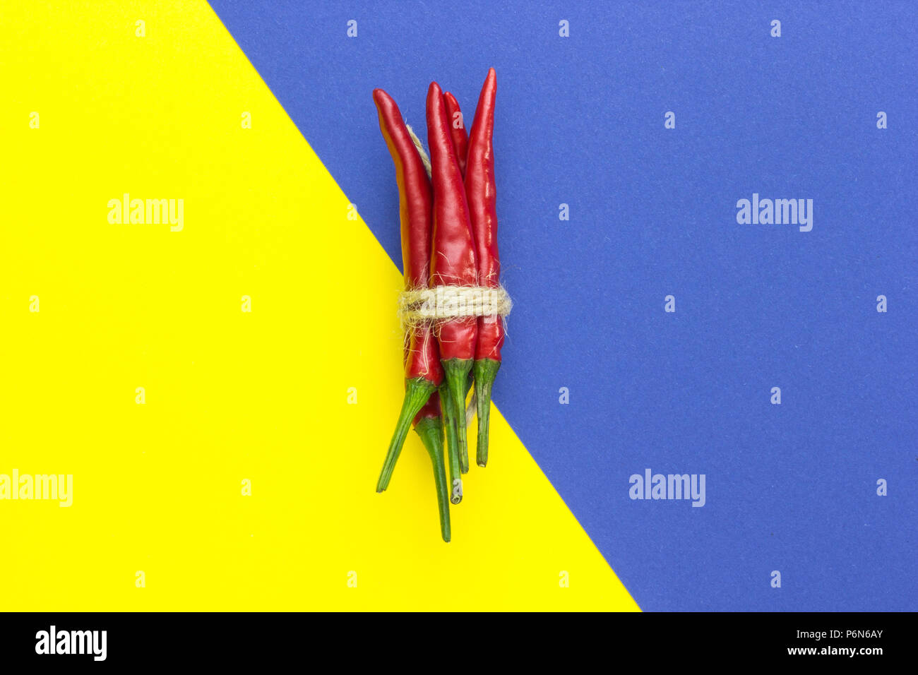 top view, red chili pepper, tied with braid on a yellow-blue background ...