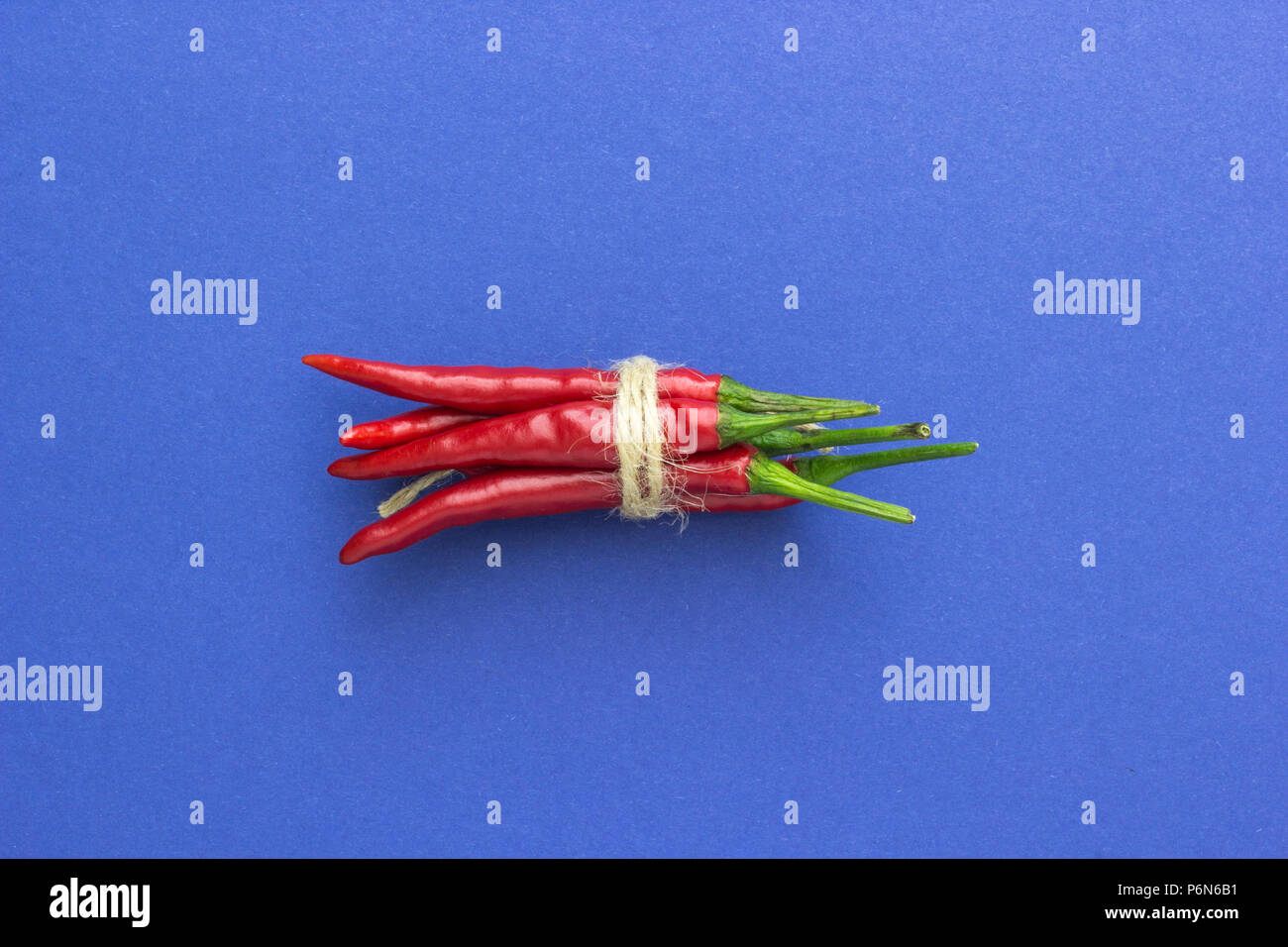 top view, red chili pepper, tied with braid on a blue background ...