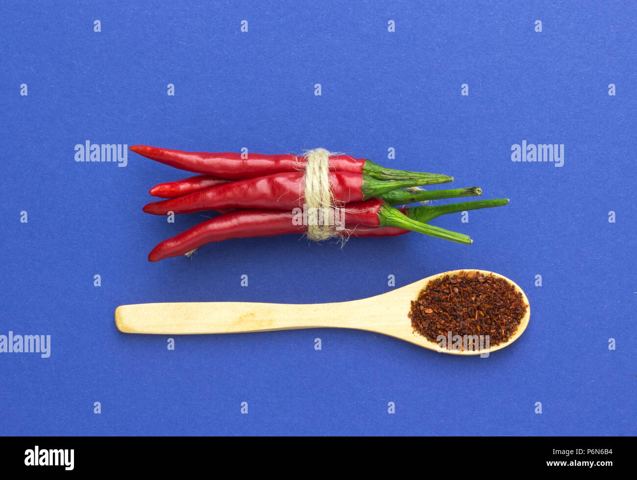 top view, red chili pepper, tied with braid and wooden spoon on a blue ...