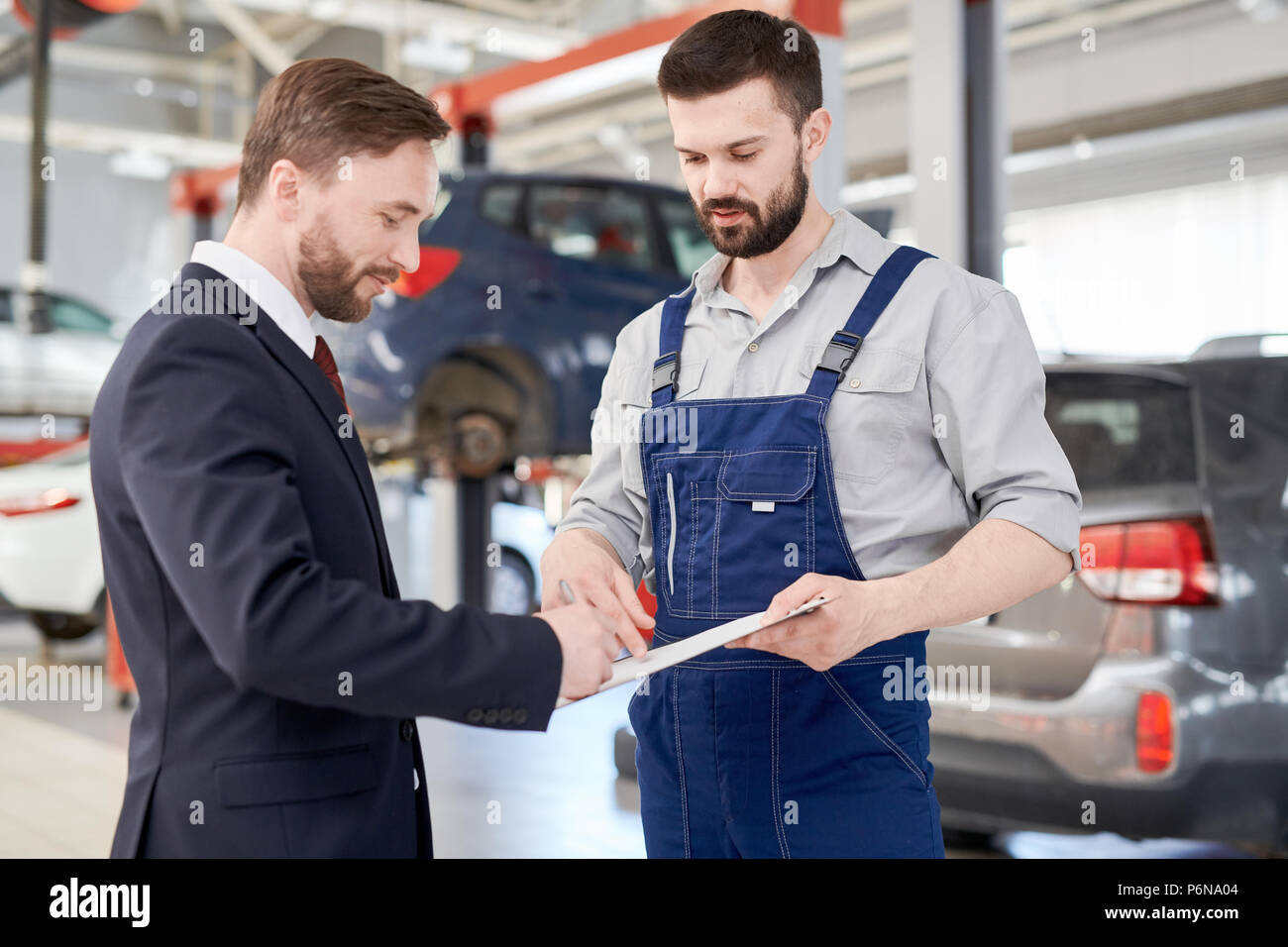 Businessman Signing Contract in Car Service Stock Photo - Alamy