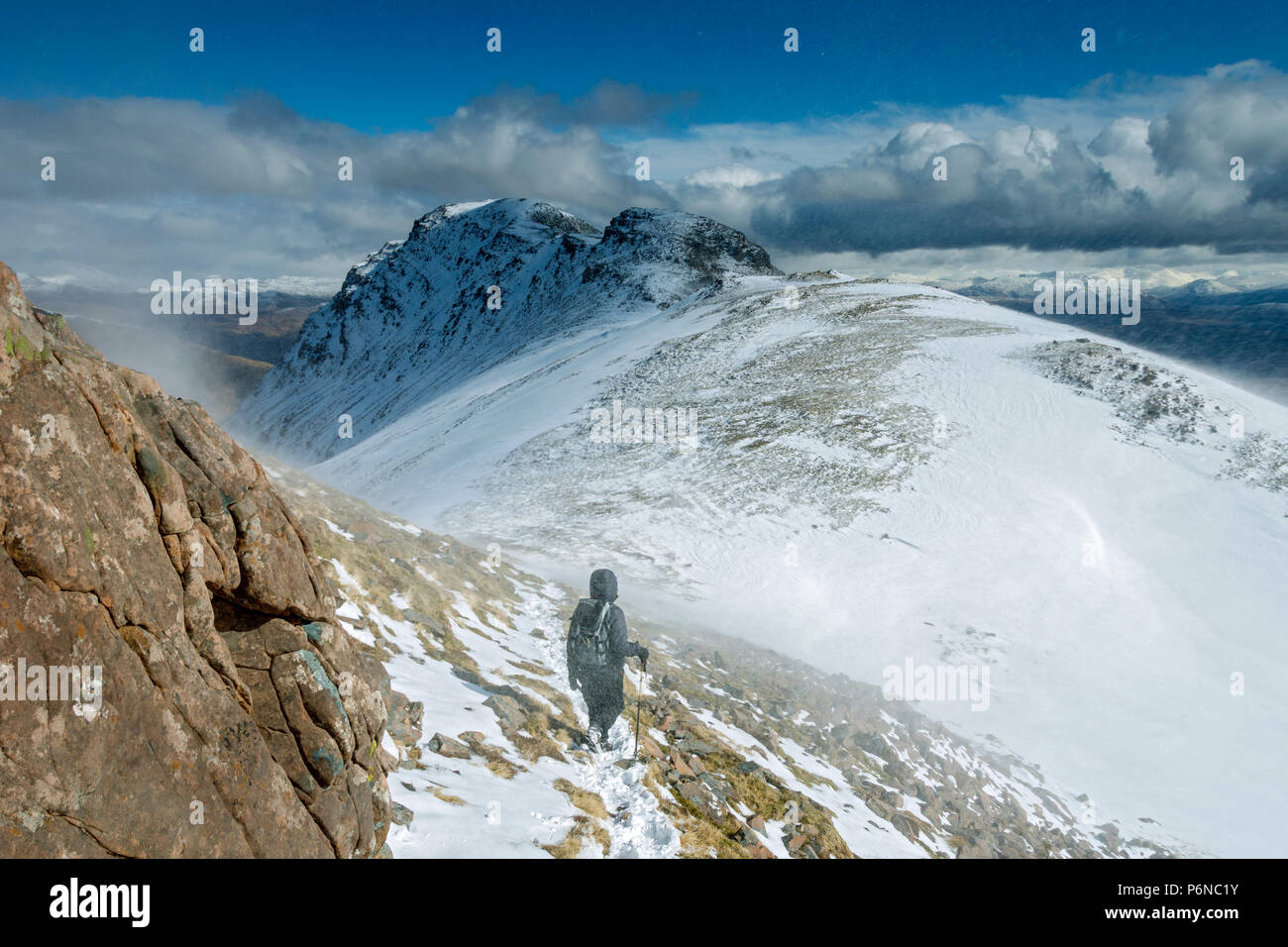 A hill walker in drifting snow, on the ridge of Sgùrr a' Chaorachain in ...