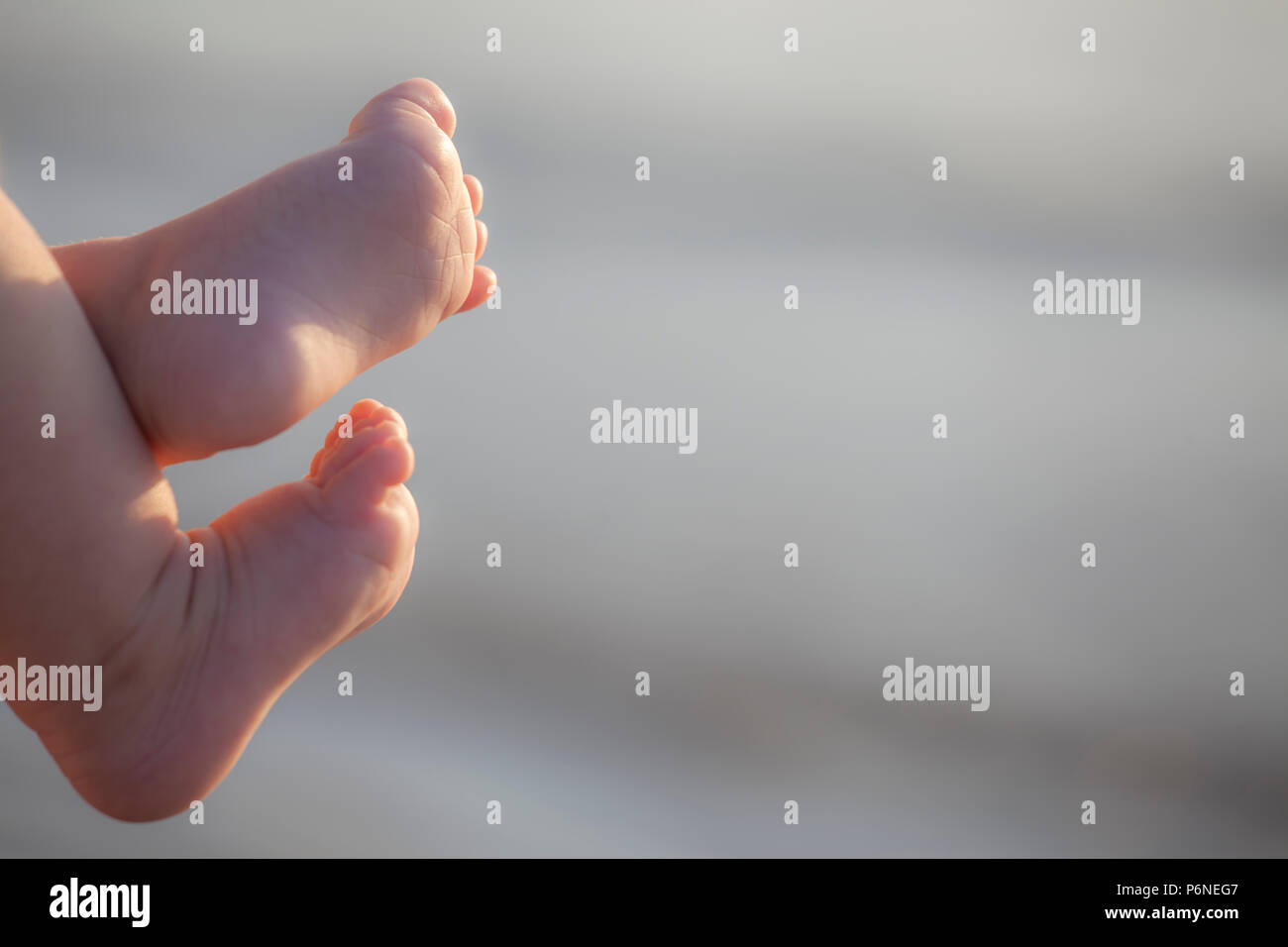 Newborn baby feet touching in summertime Stock Photo - Alamy