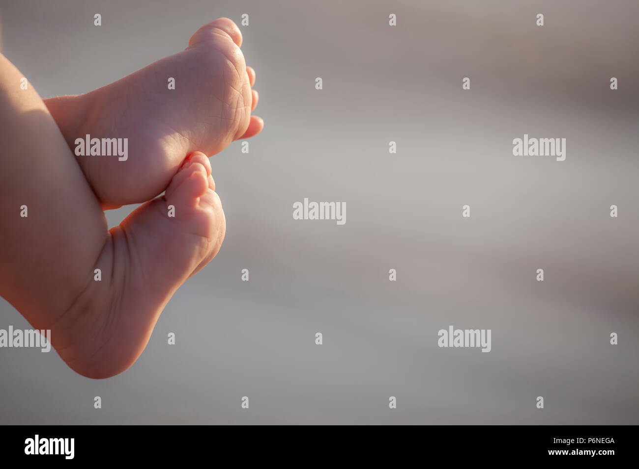 Newborn baby feet touching in summertime Stock Photo - Alamy
