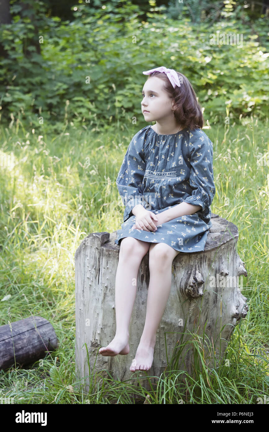 little girl is sitting on a stump in the forest, a lost child portrait ...